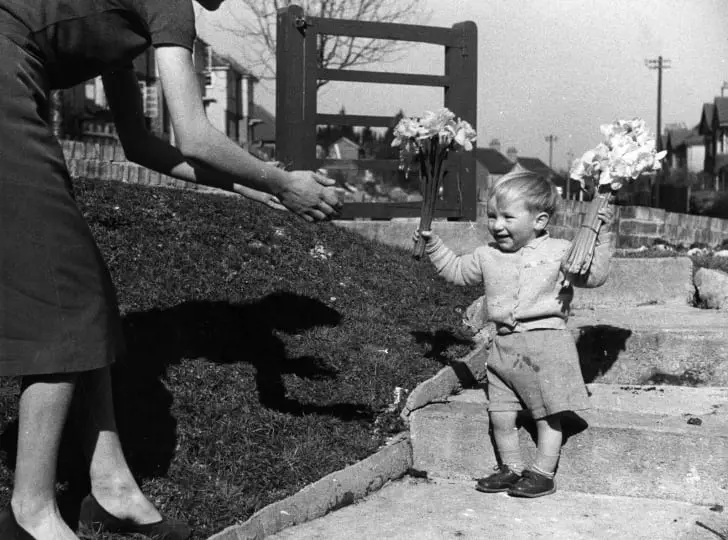 Un niño le da flores a su madre.