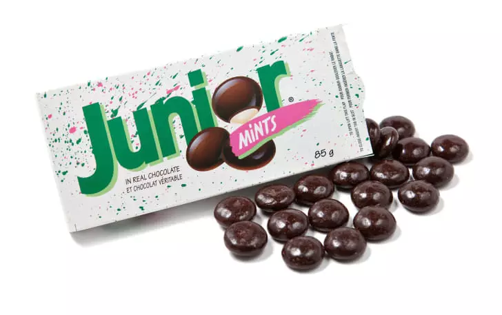 Egy nyitott doboz Junior Mints cukorka fehér alapon.