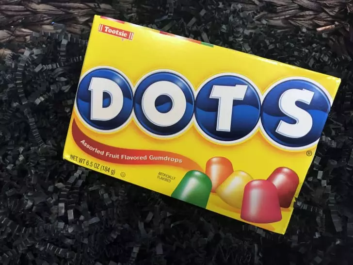 Bocs o gumdrops DOTS ar gefndir du.